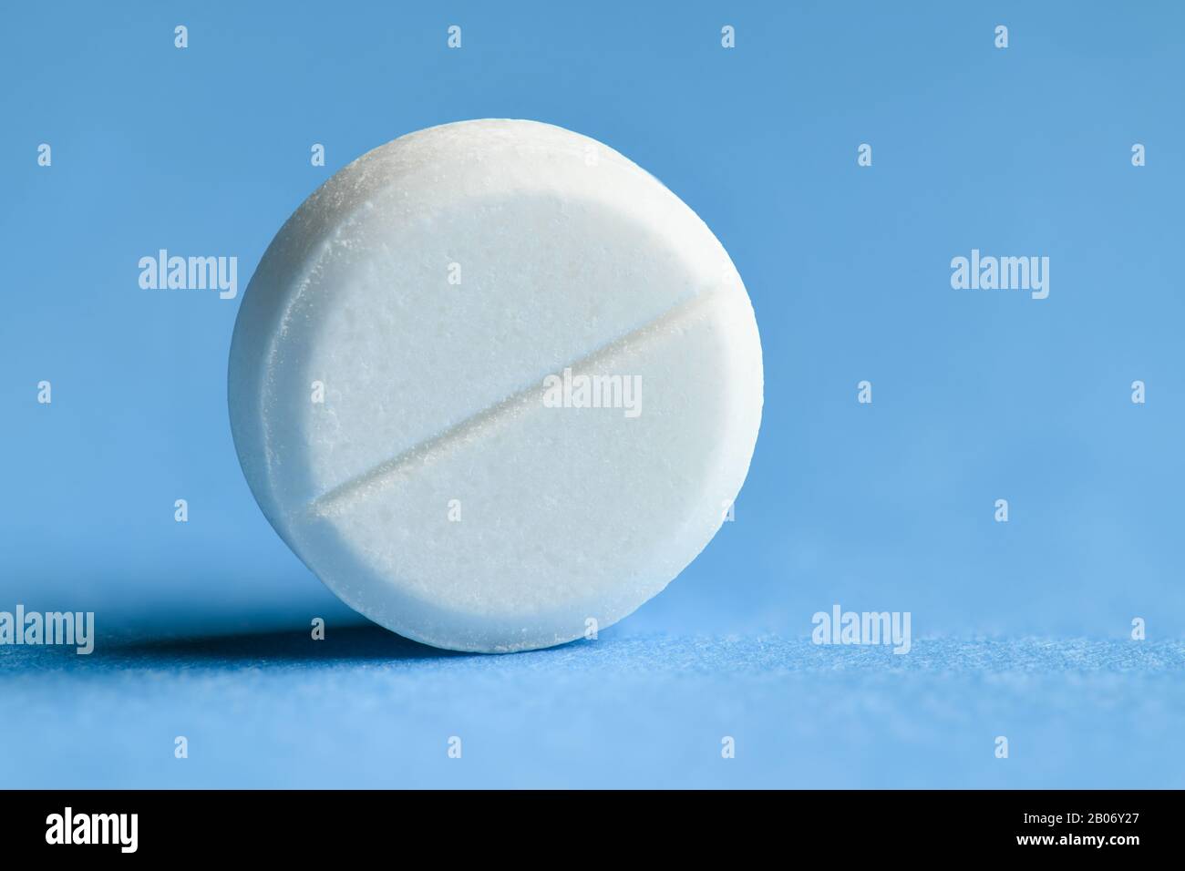 One white pill on blue background macro photo - concept of medicine and ...