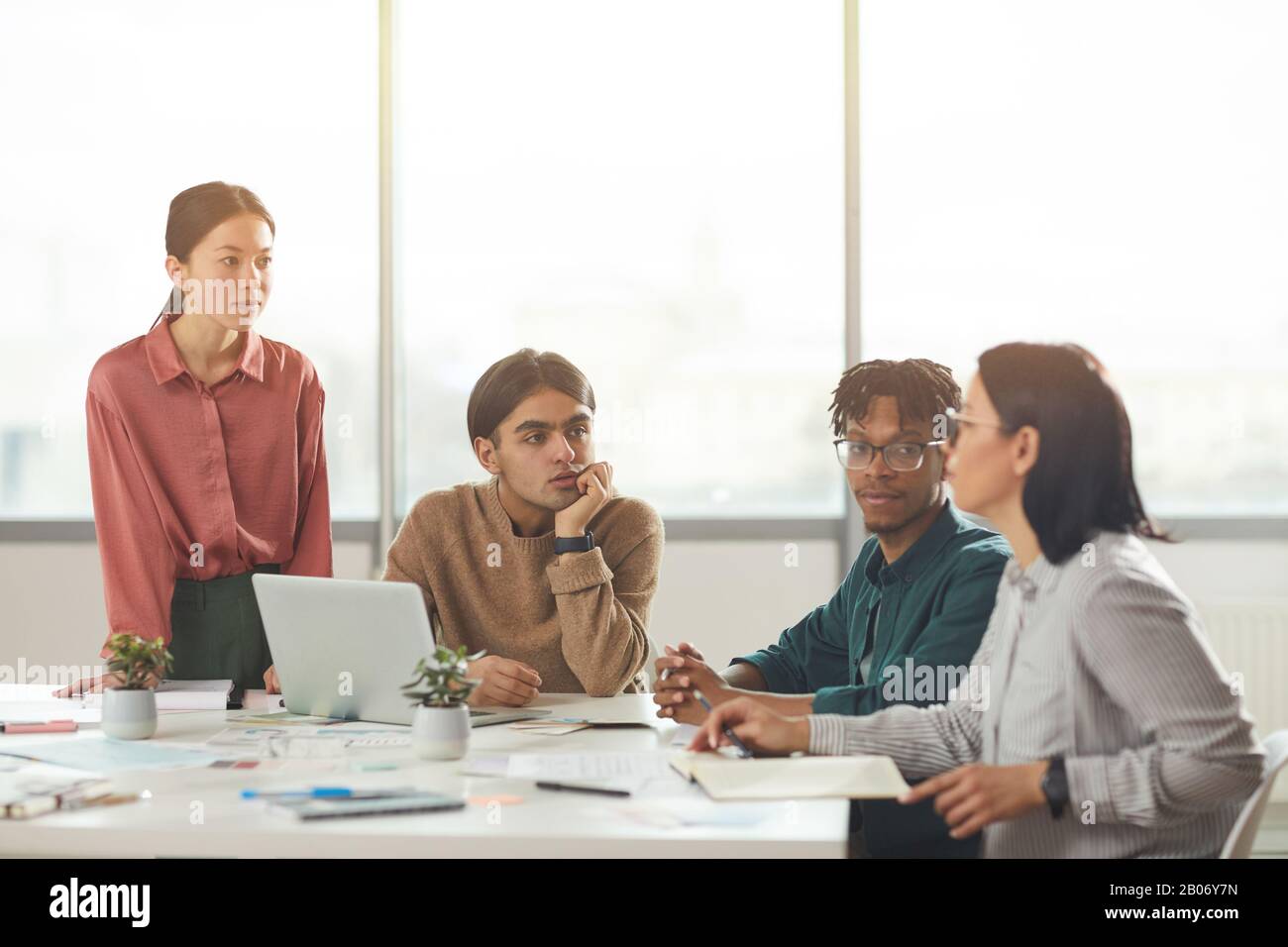 Group of young designers sitting at the table during a meeting and ...