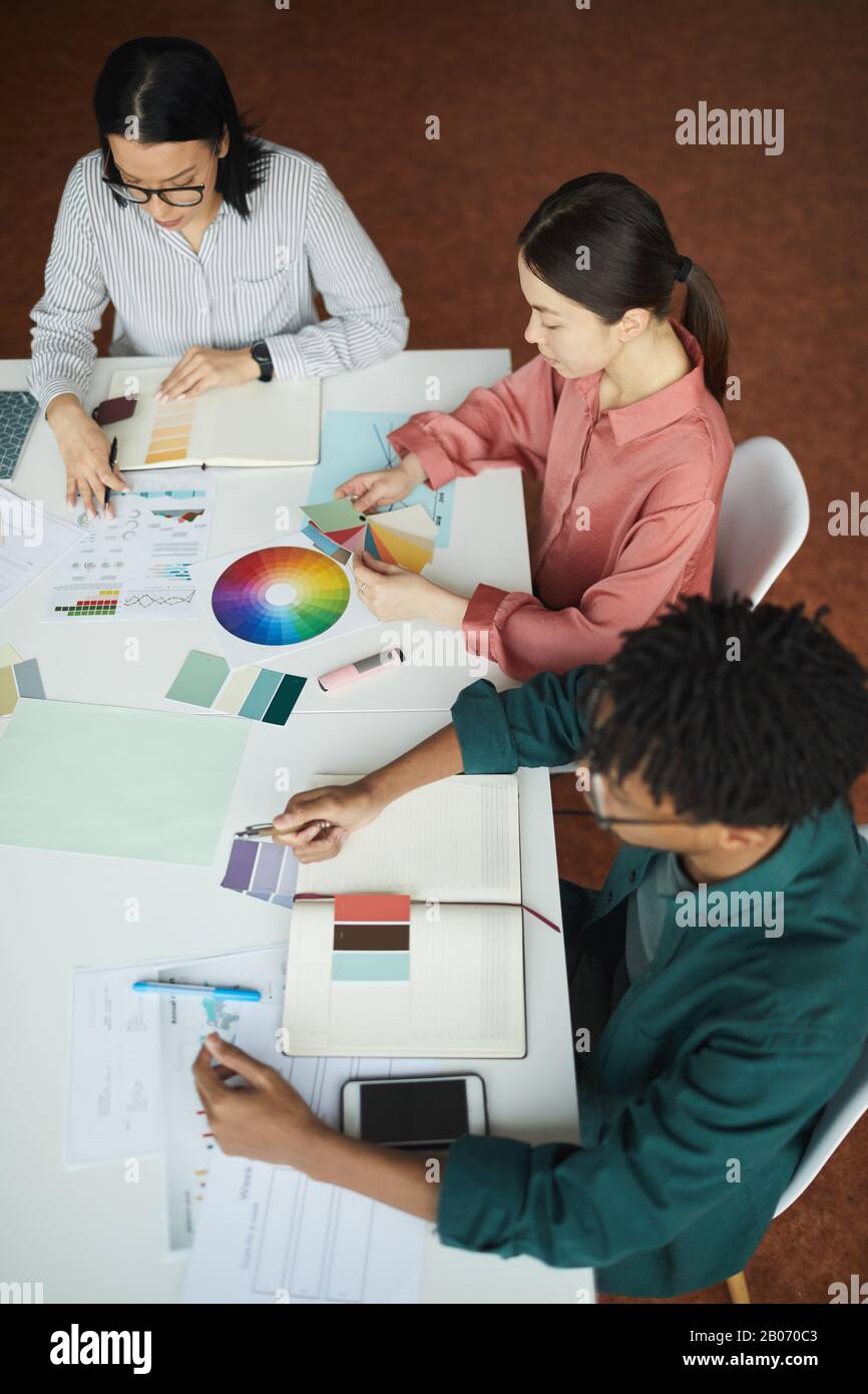 Team of designers sitting at the table and choosing color for new ...