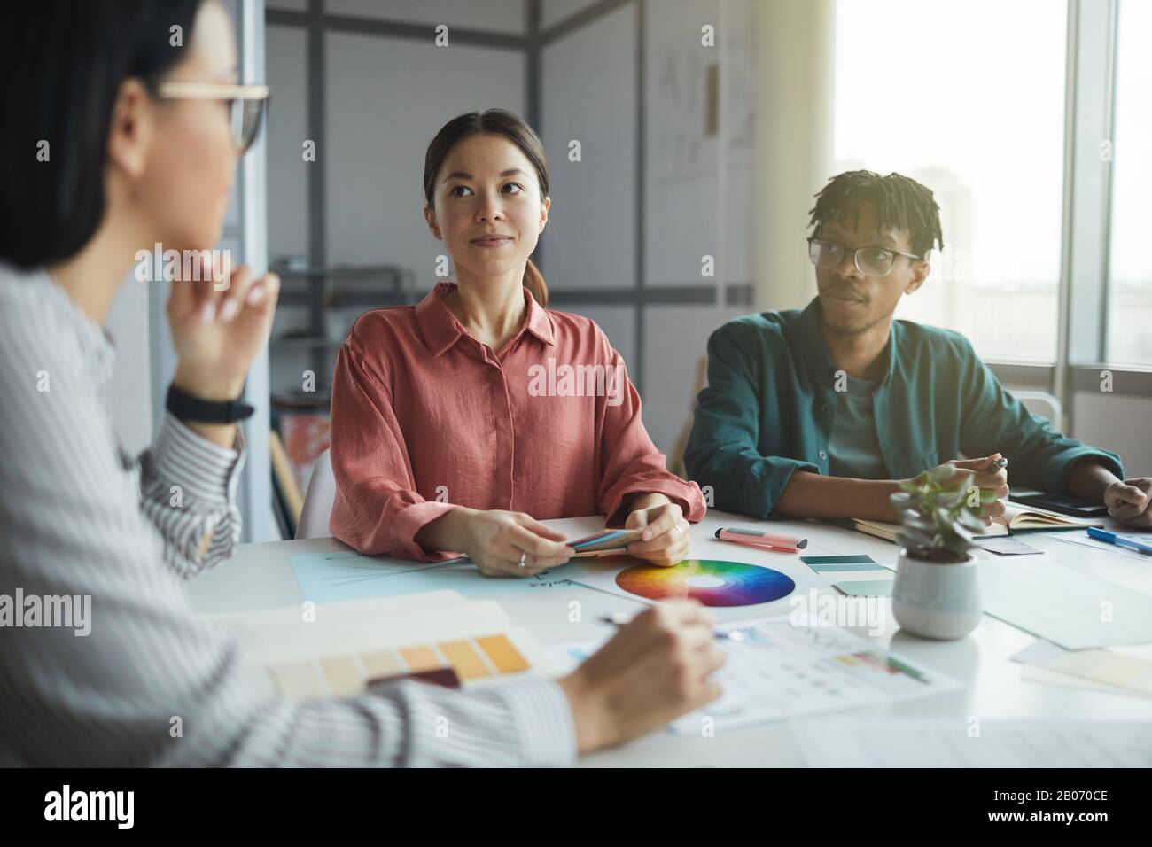 Two young designers sitting at the table with customer and discussing ...