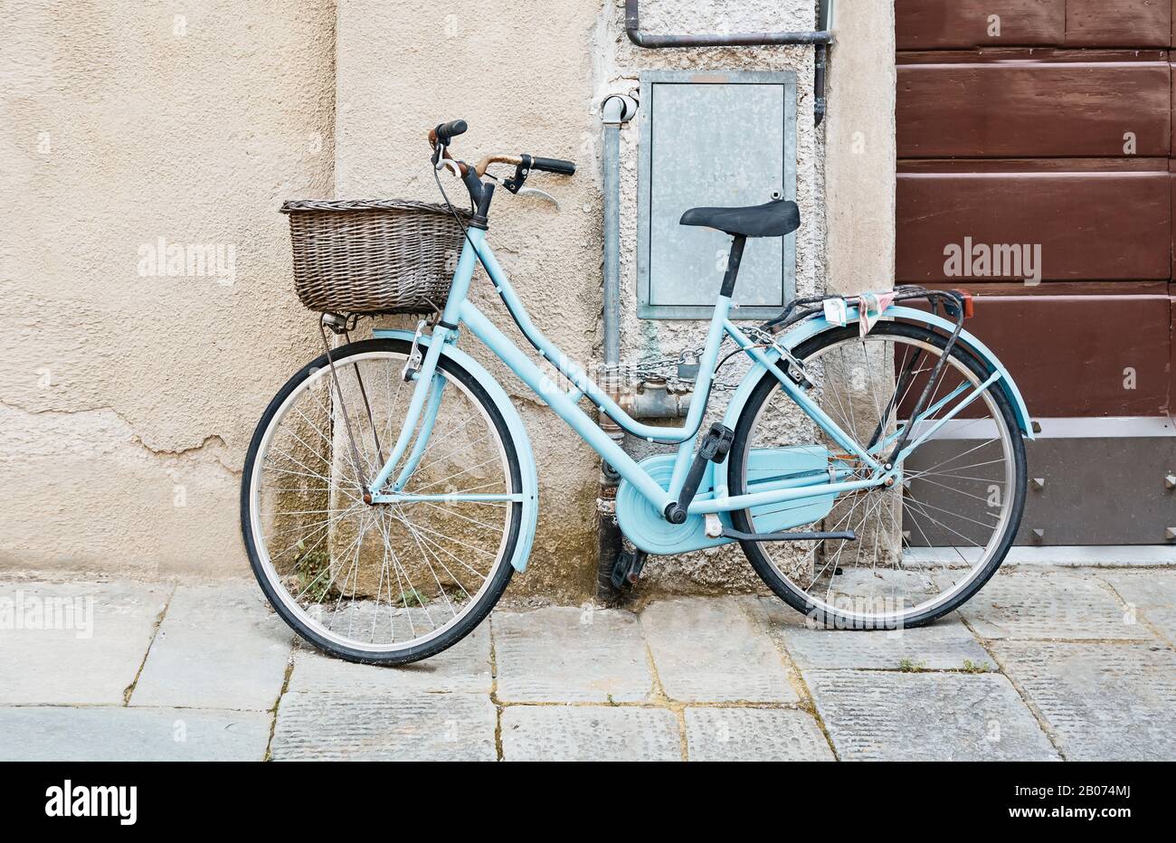 light blue bike with bastket leaning against the wall Stock Photo - Alamy