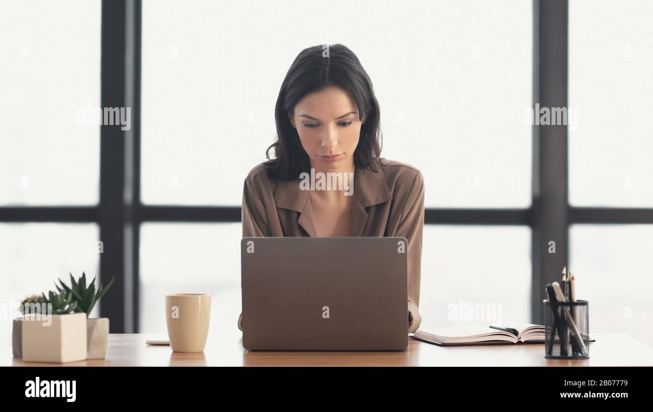 Beautiful girl working on her laptop at new office Stock Photo - Alamy