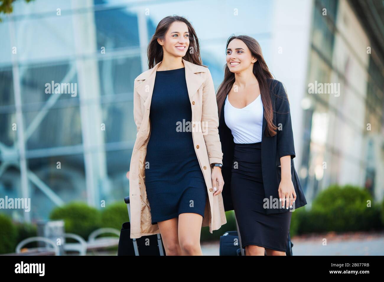 Vacation. Two happy girls traveling abroad together, carrying suitcase ...