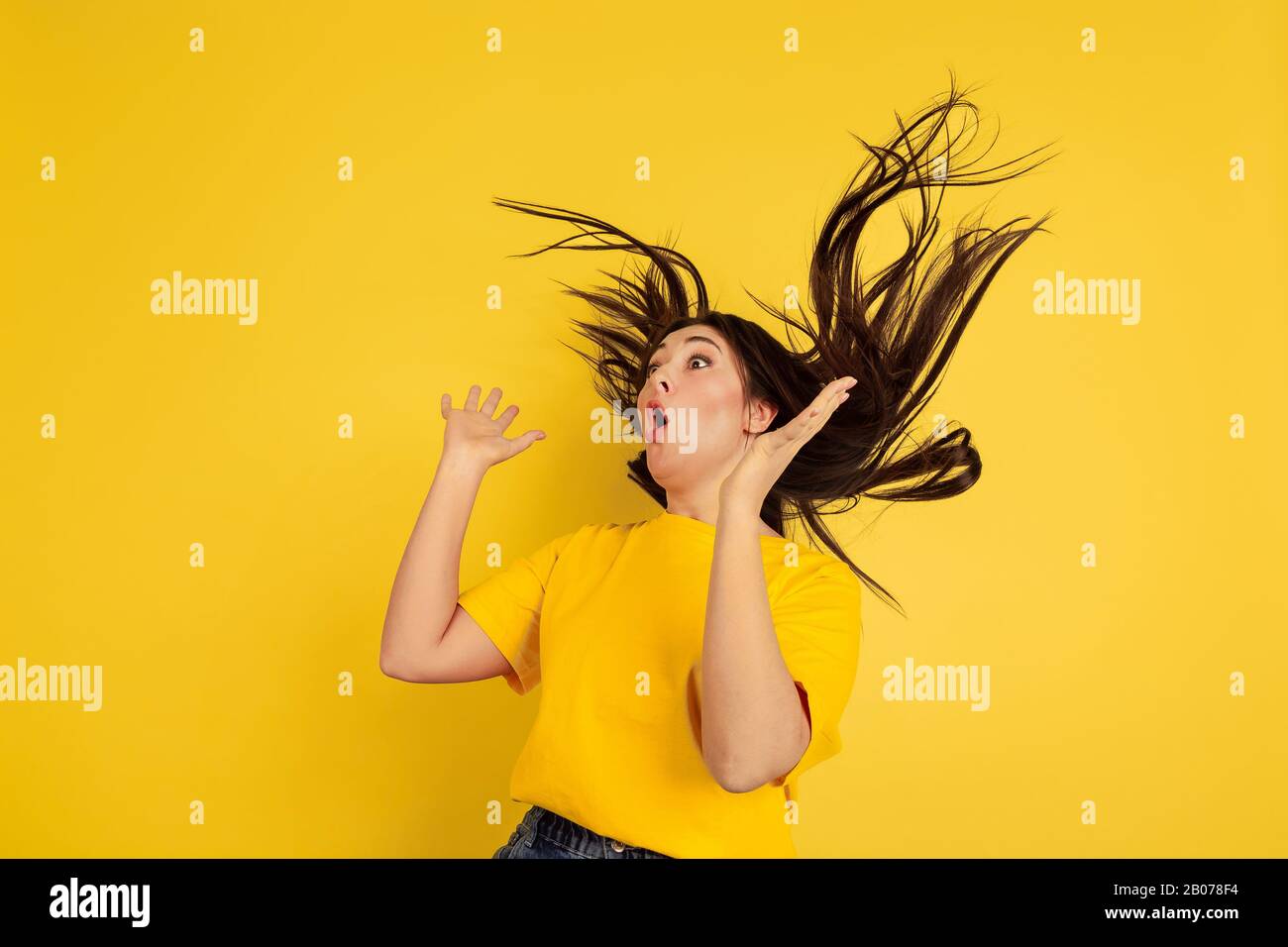 Astonished crazy. Caucasian woman's portrait isolated on yellow studio ...