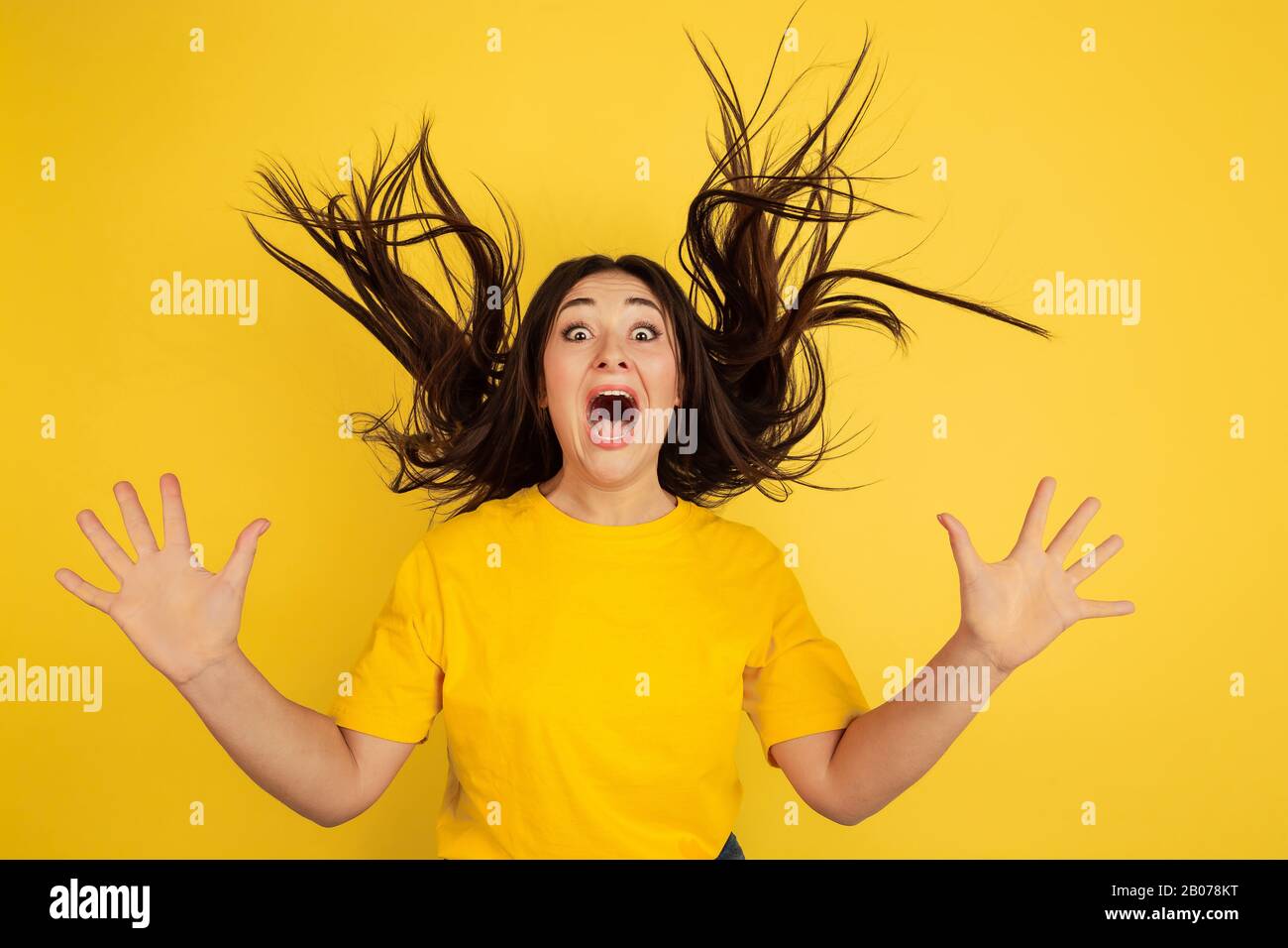 Astonished, crazy. Caucasian woman's portrait isolated on yellow studio ...
