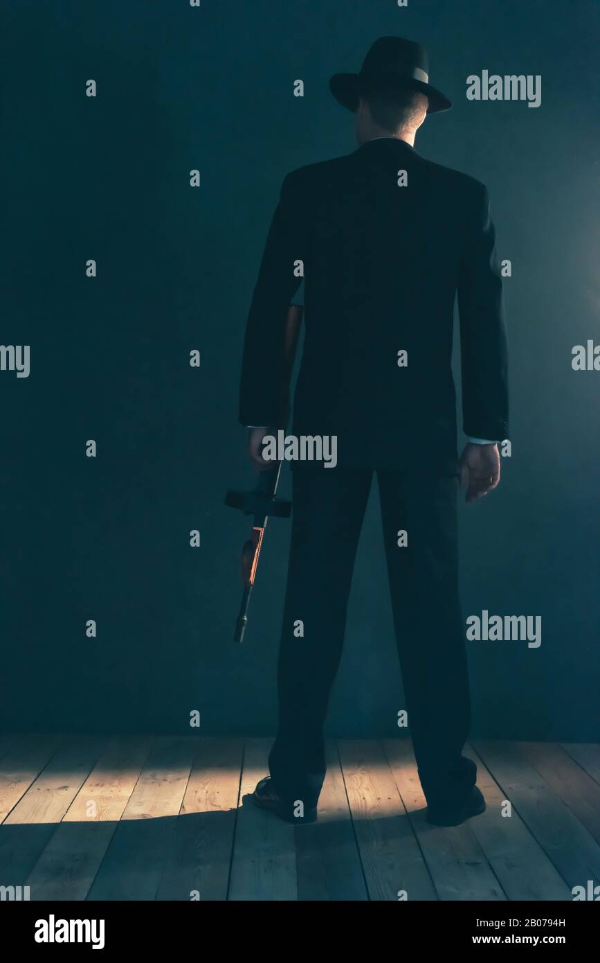 Retro gangster stands with machine gun. Rear view Stock Photo - Alamy