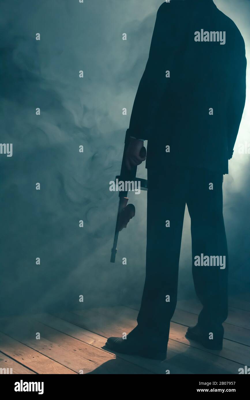 Retro gangster stands with machine gun in smoky room. Rear view Stock ...