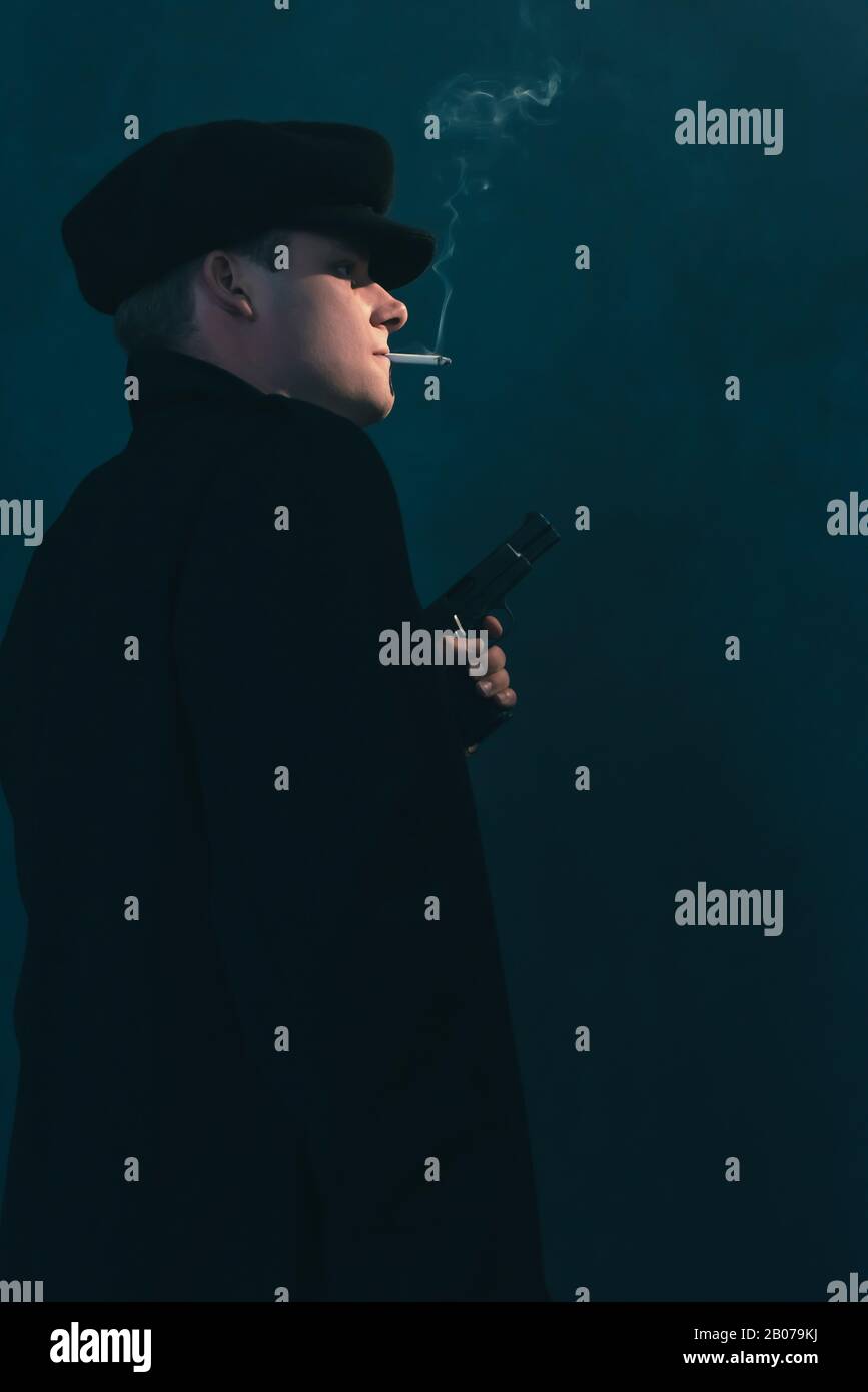 Retro mobster with cigarette holds gun. Side view Stock Photo - Alamy