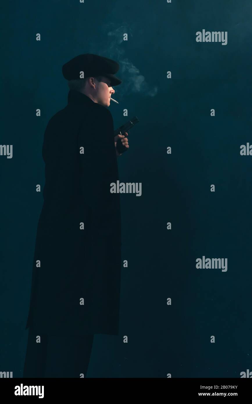 Retro mobster with cigarette holds gun. Side view Stock Photo - Alamy