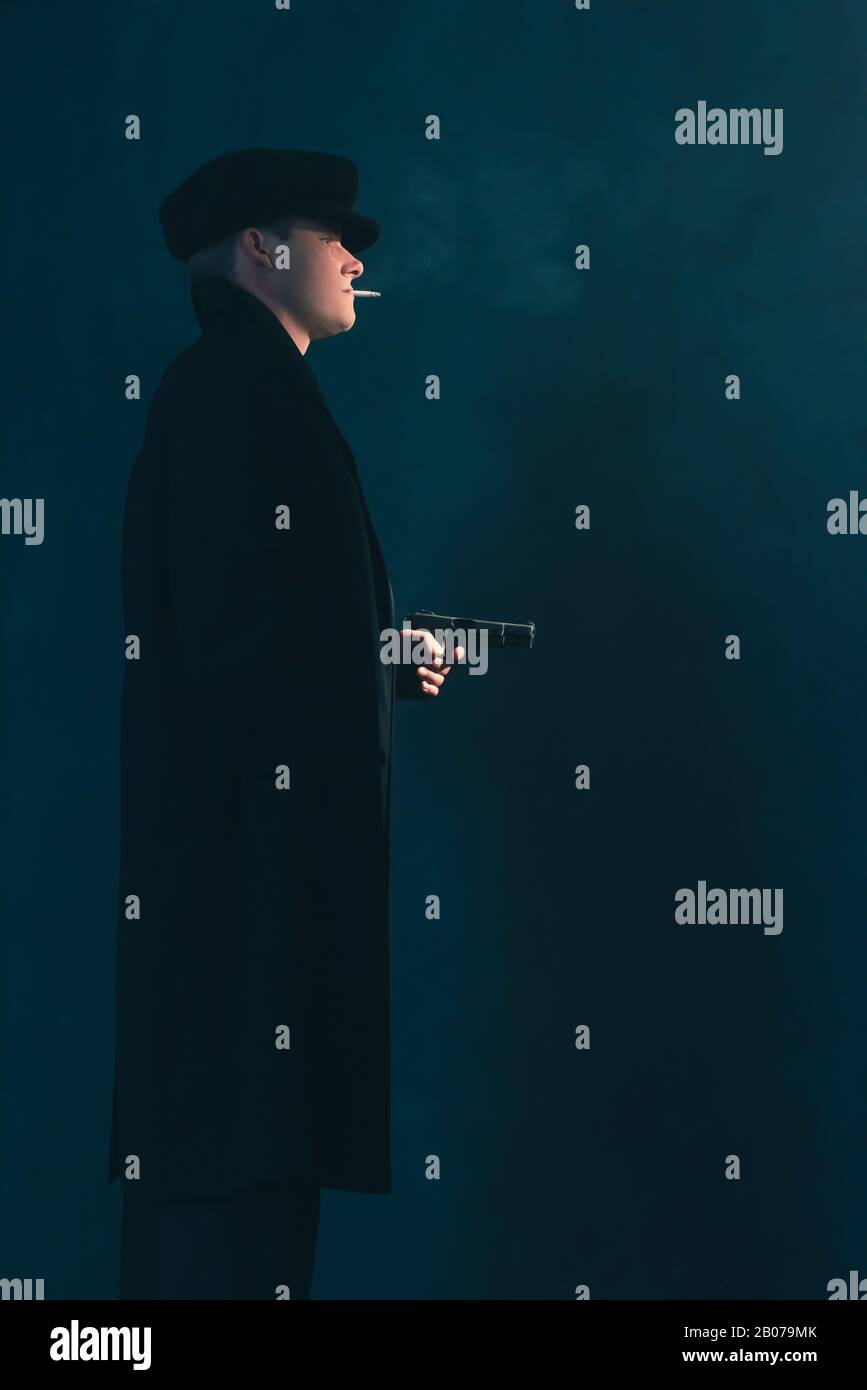 Retro mobster with cigarette shoots with gun. Side view Stock Photo - Alamy