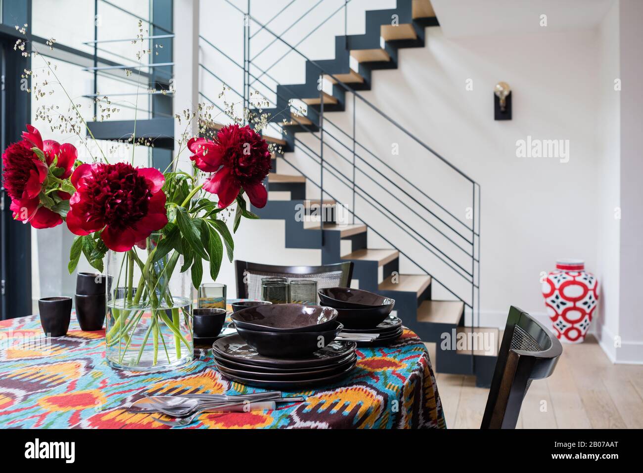 Colourful dining table by staircase Stock Photo - Alamy