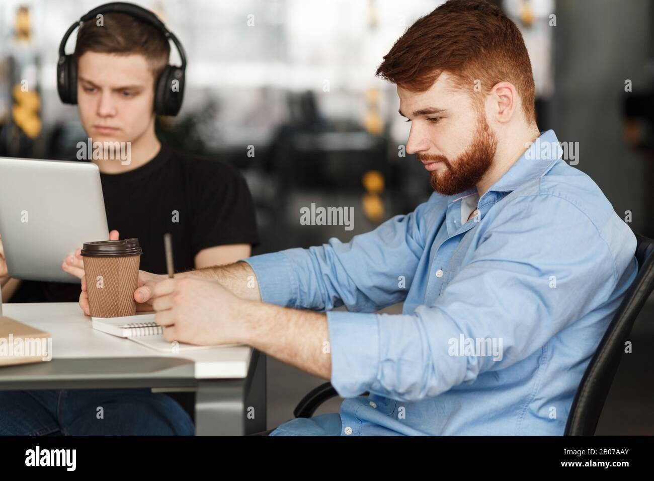 Concentrated student guy writing essay in library Stock Photo - Alamy