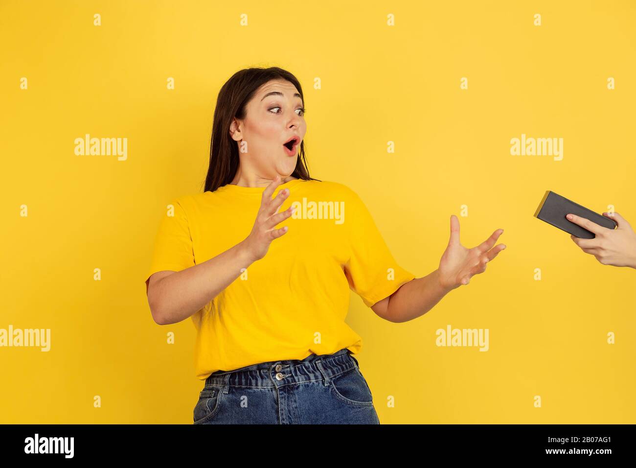 Taking a gift. Caucasian woman's portrait isolated on yellow studio ...