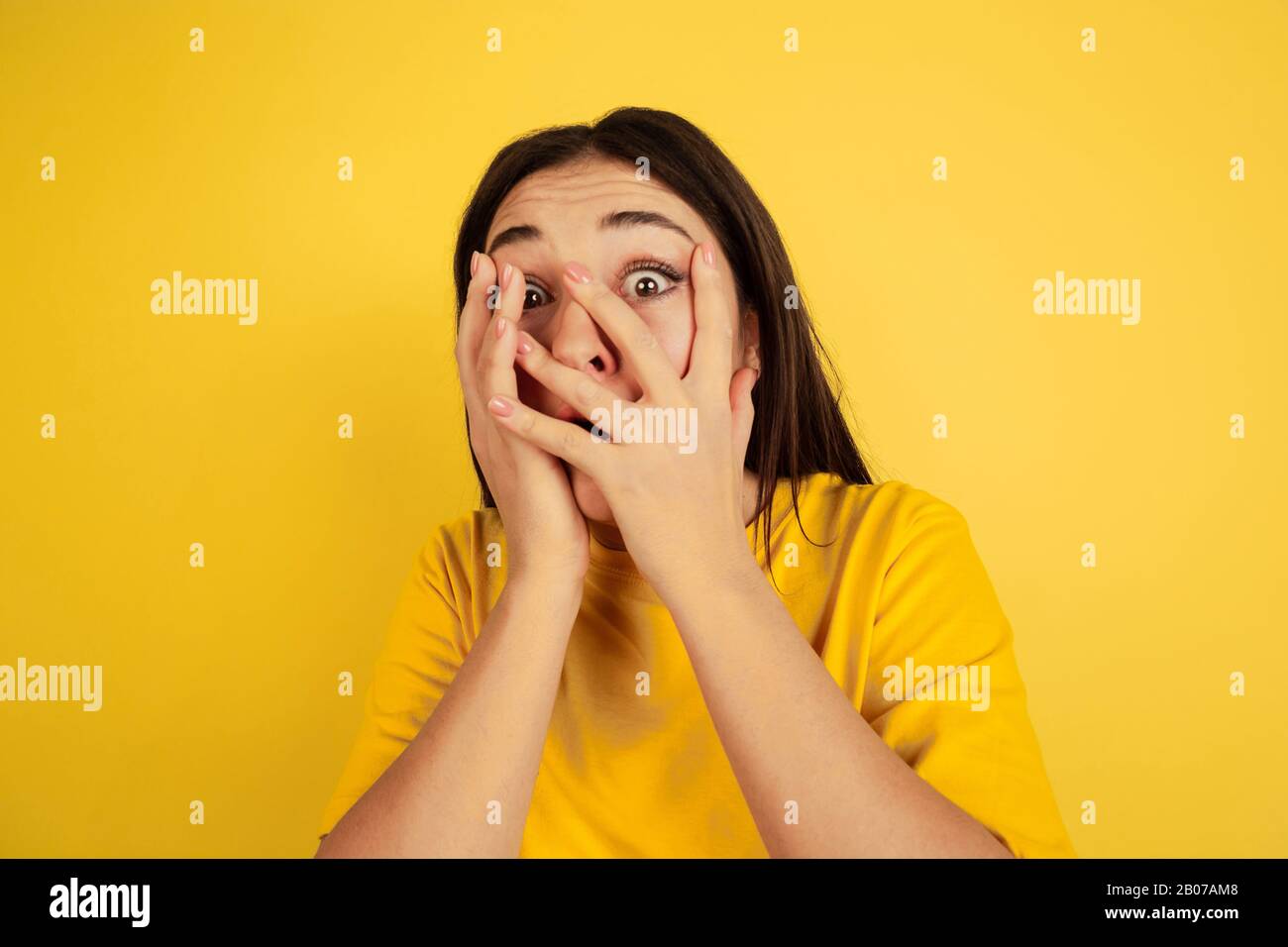 Shocked, scared. Caucasian woman's portrait isolated on yellow studio ...