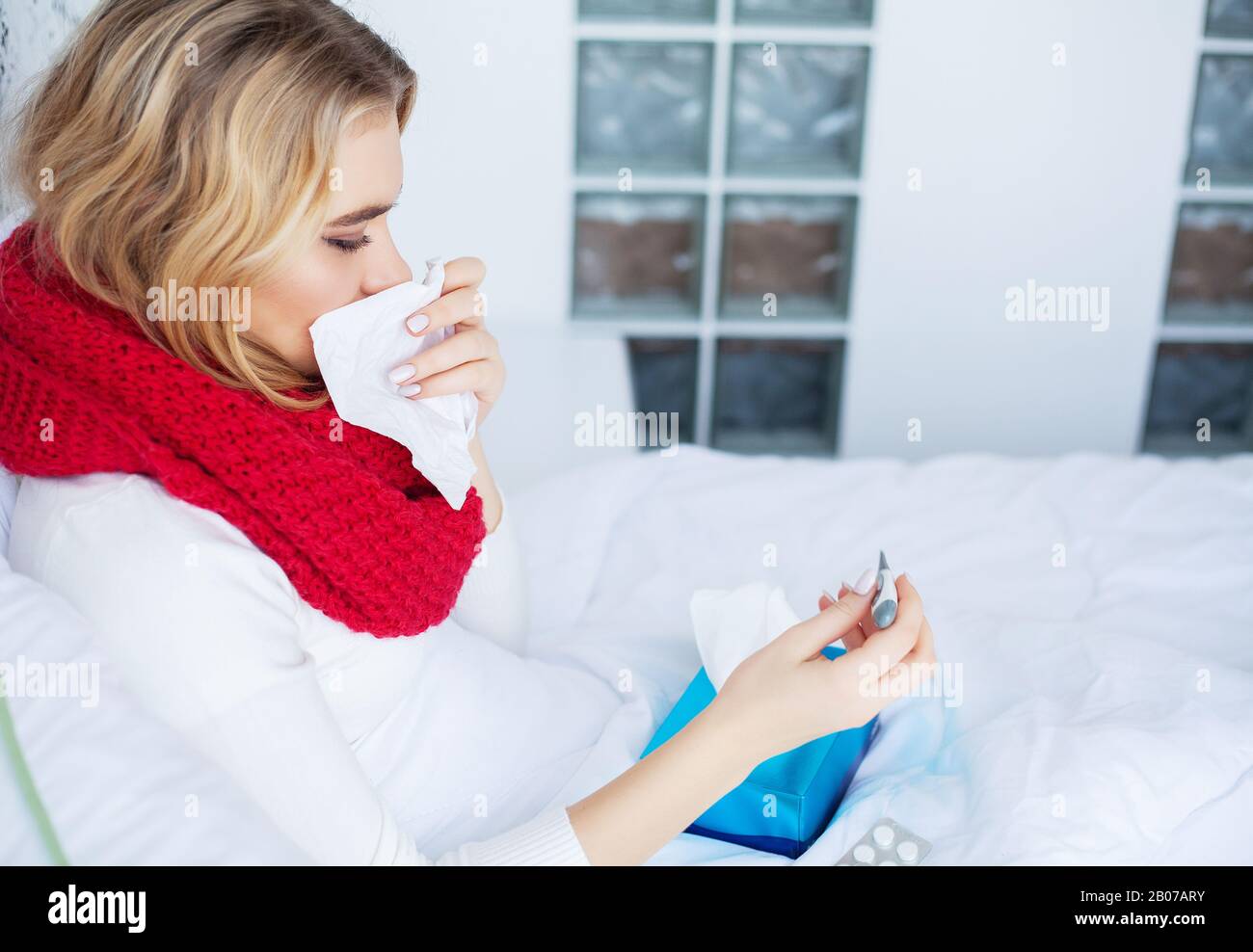Sick Woman. Woman with flu virus lying in bed, she is measuring her ...