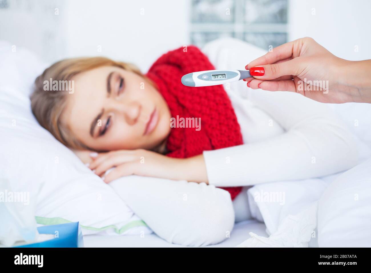 Sick Woman. Woman with flu virus lying in bed, she is measuring her ...