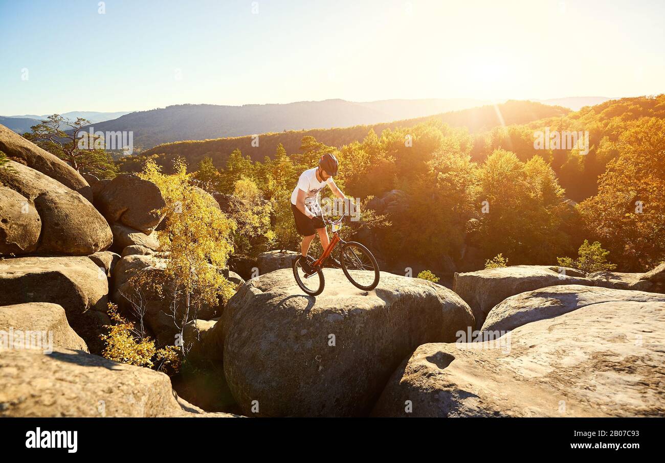 Athlete cyclist balancing on back wheel on trial bike, sportsman rider ...