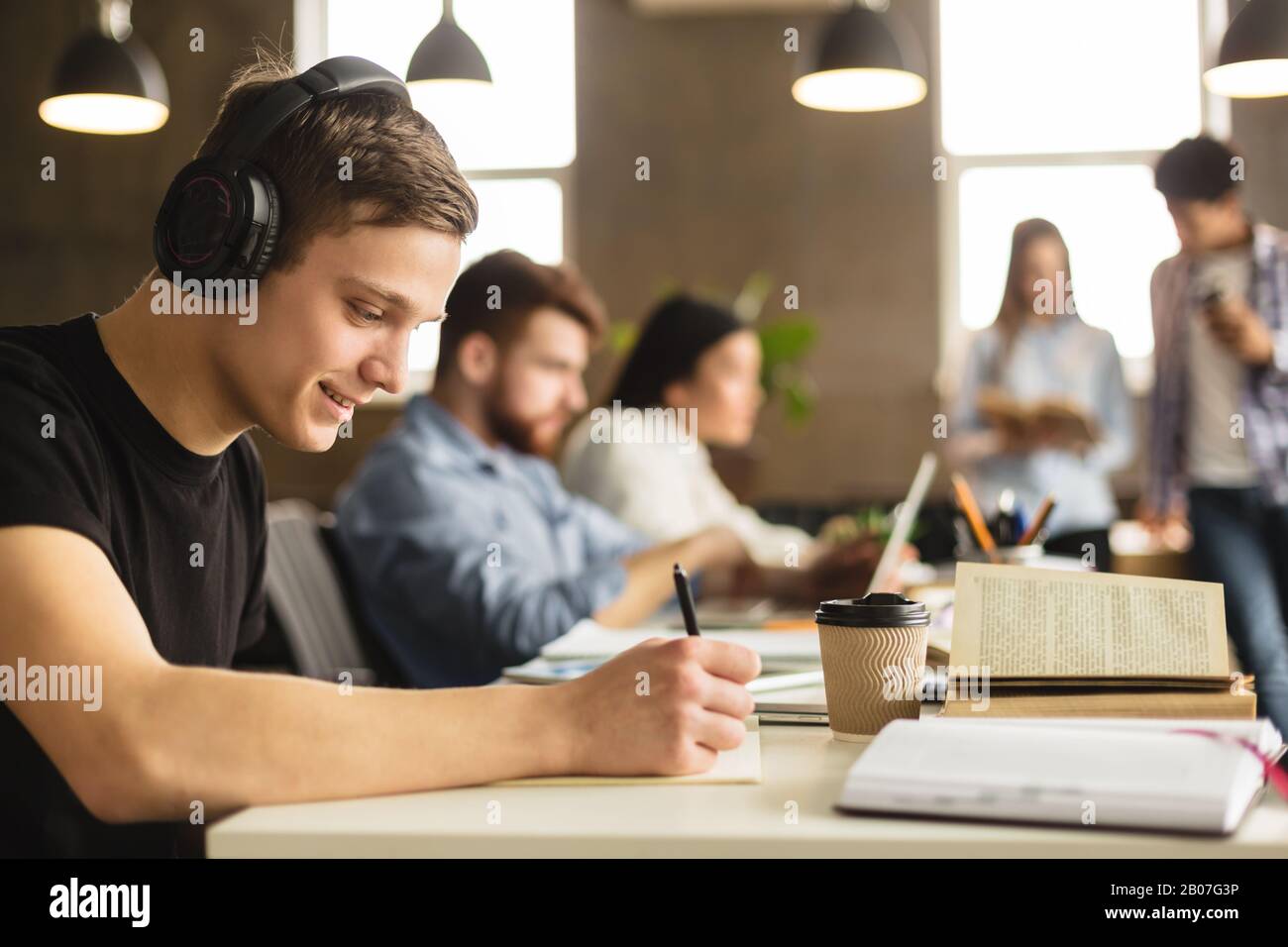 Confident student. Guy sitting at library, taking notes Stock Photo - Alamy