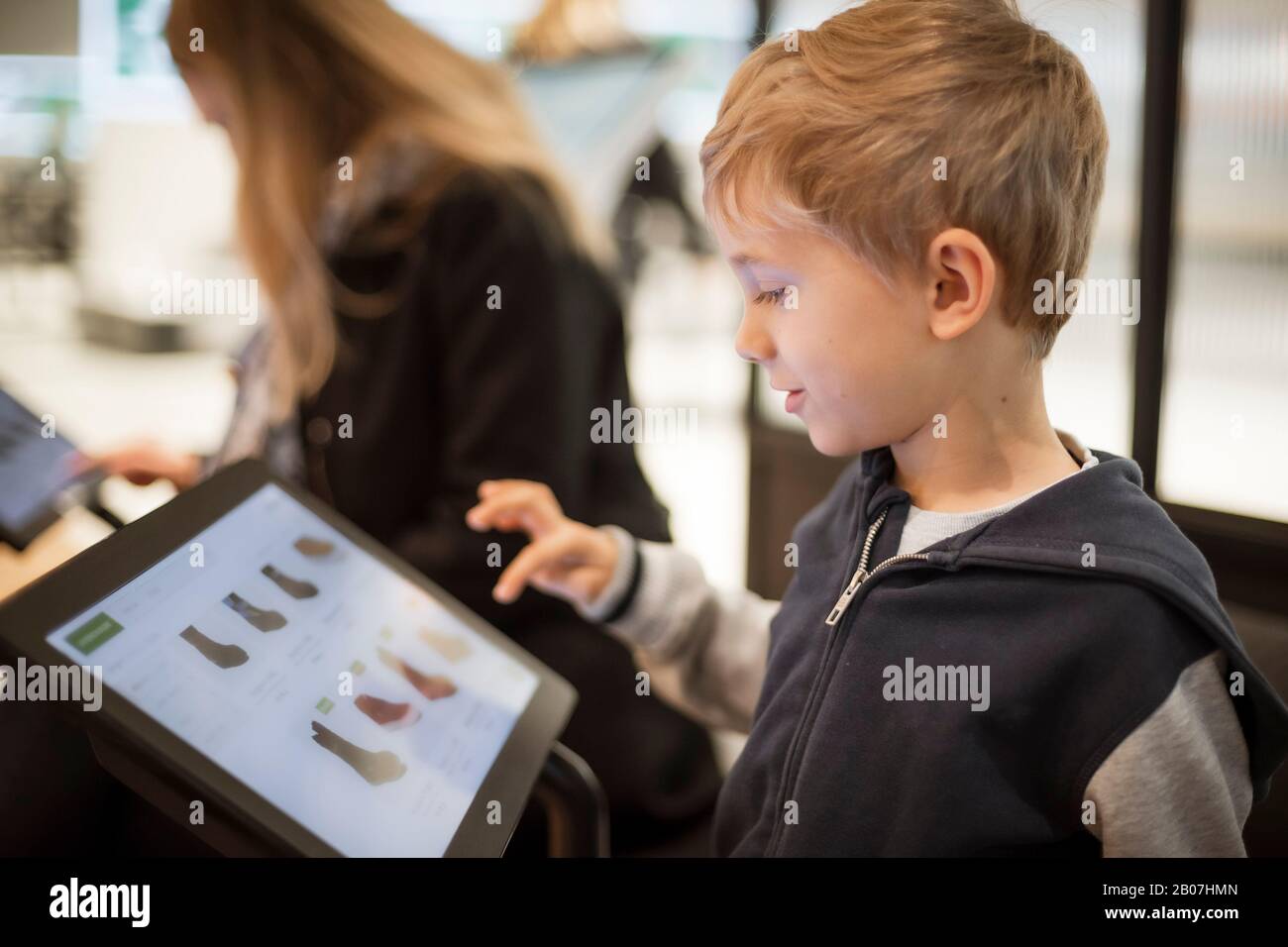 Young boy chooses shopping on the monitor screen in a modern store ...