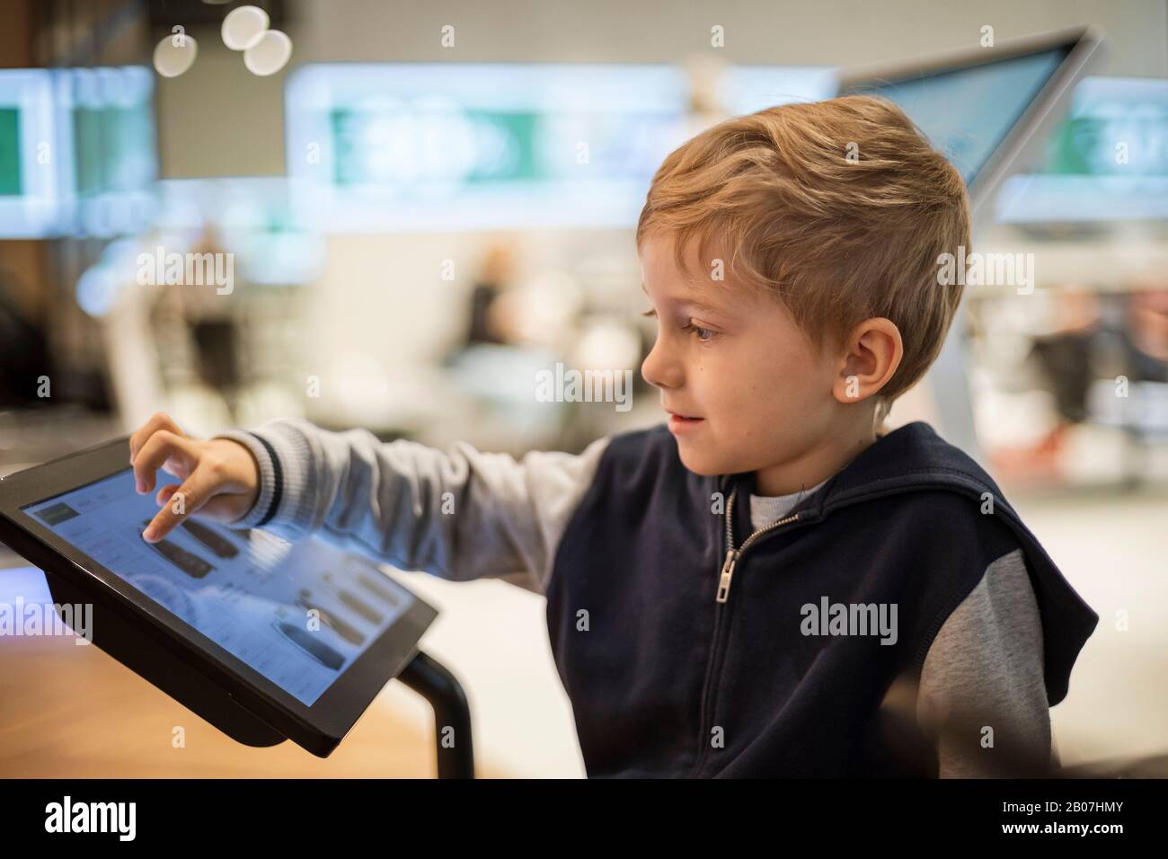 Young boy chooses shopping on the monitor screen in a modern store ...