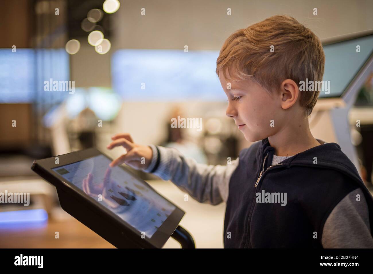 Young boy chooses shopping on the monitor screen in a modern store ...