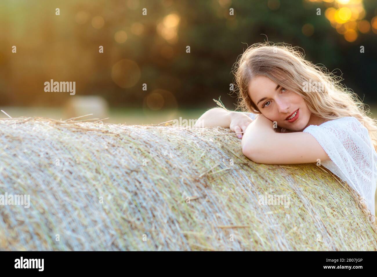 Emotional portrait of a cheerful blonde girl in a countryside landscape ...