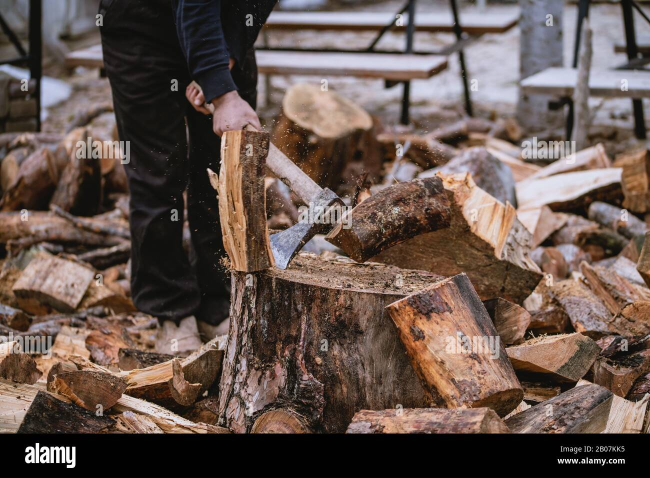 Man is chopping wood with vintage axe. Detail of flying pieces of wood ...
