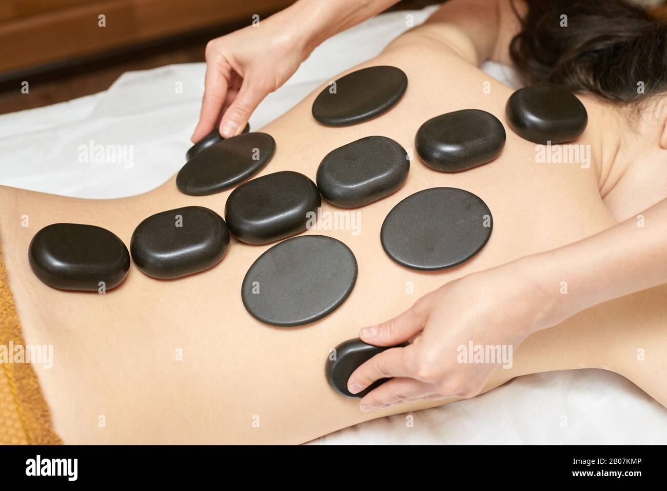 body stone massage. Hot rock masseur. Girl at salon with doctor hands ...