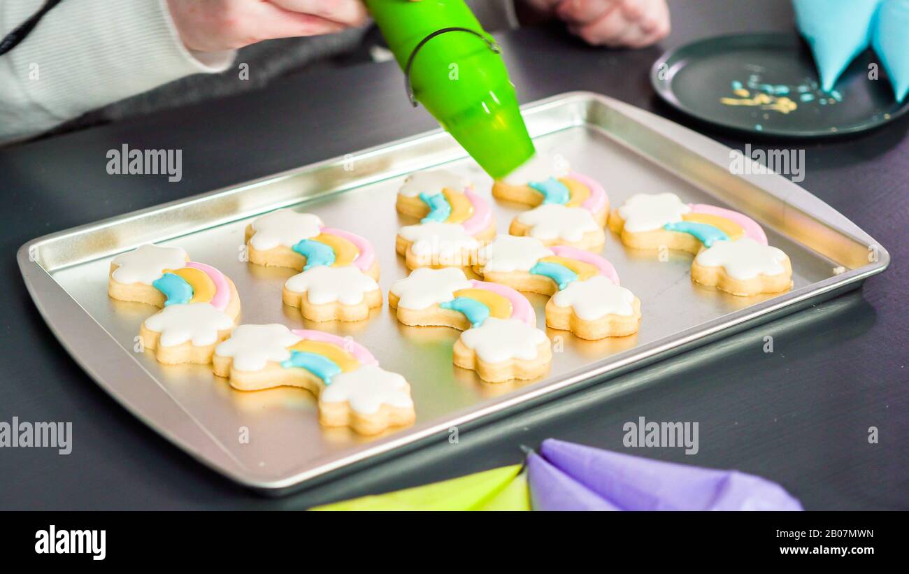 Decorating unicorn sugar cookies with multi-color royal icing Stock ...