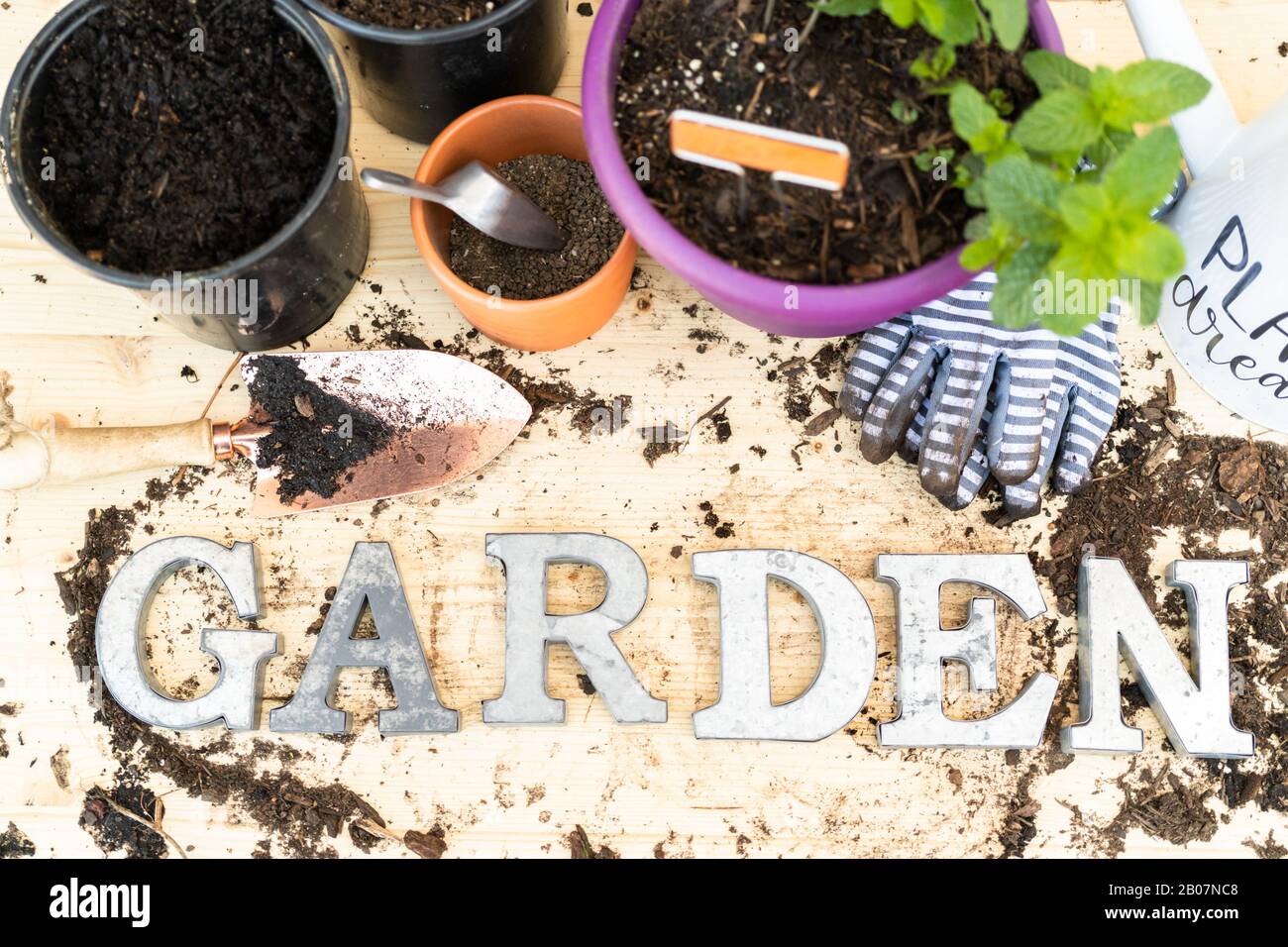 Sign GARDEN in metal letters around spilled soil and planting pots on a ...