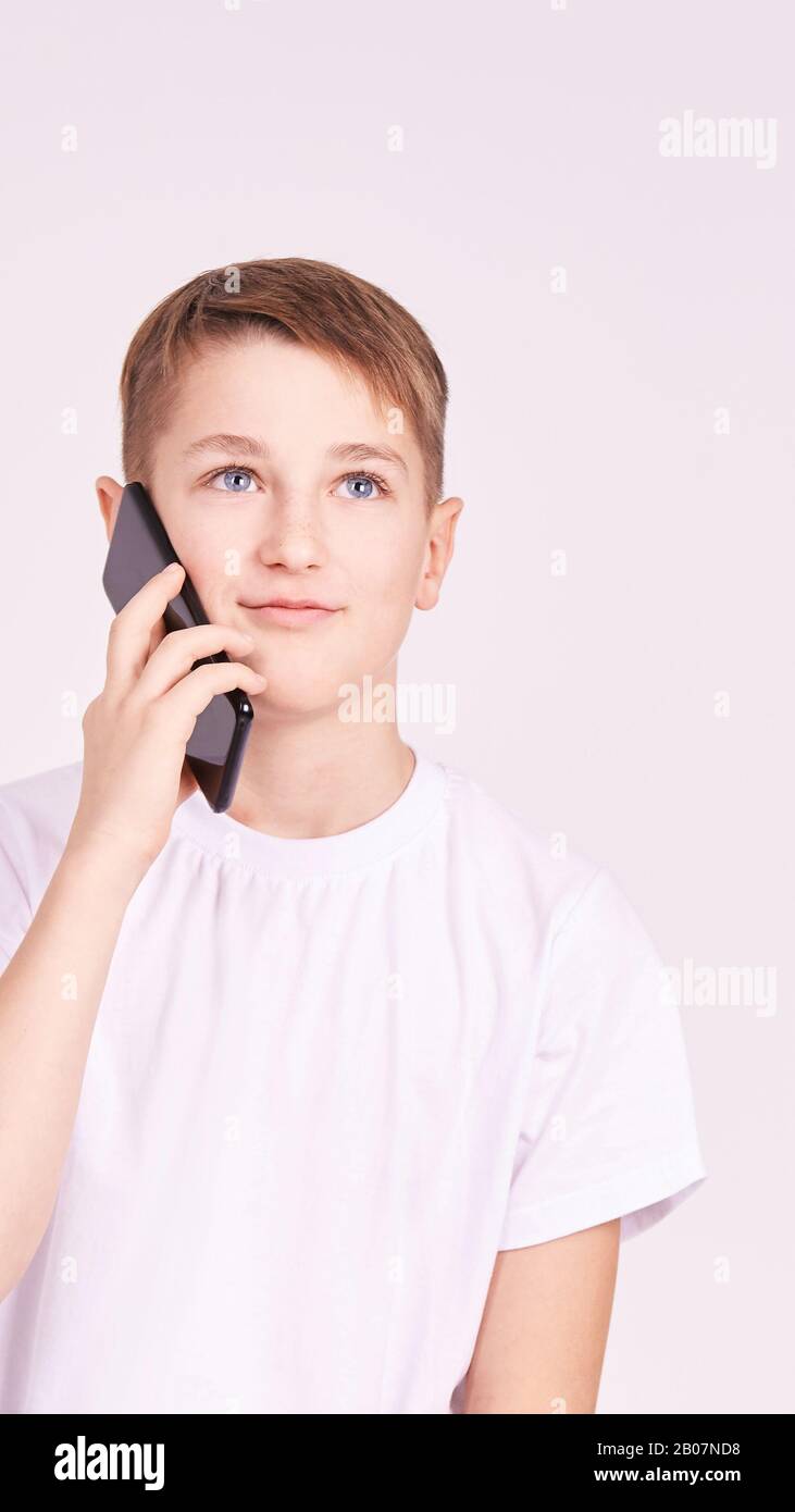 Young boy talking telephone. White shirt at grey background. Male ...