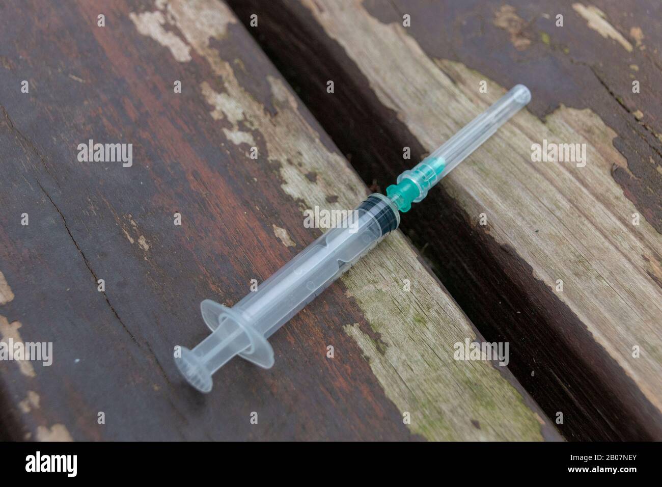 A close view of a used small gadge needle and saringe on a old wooden ...