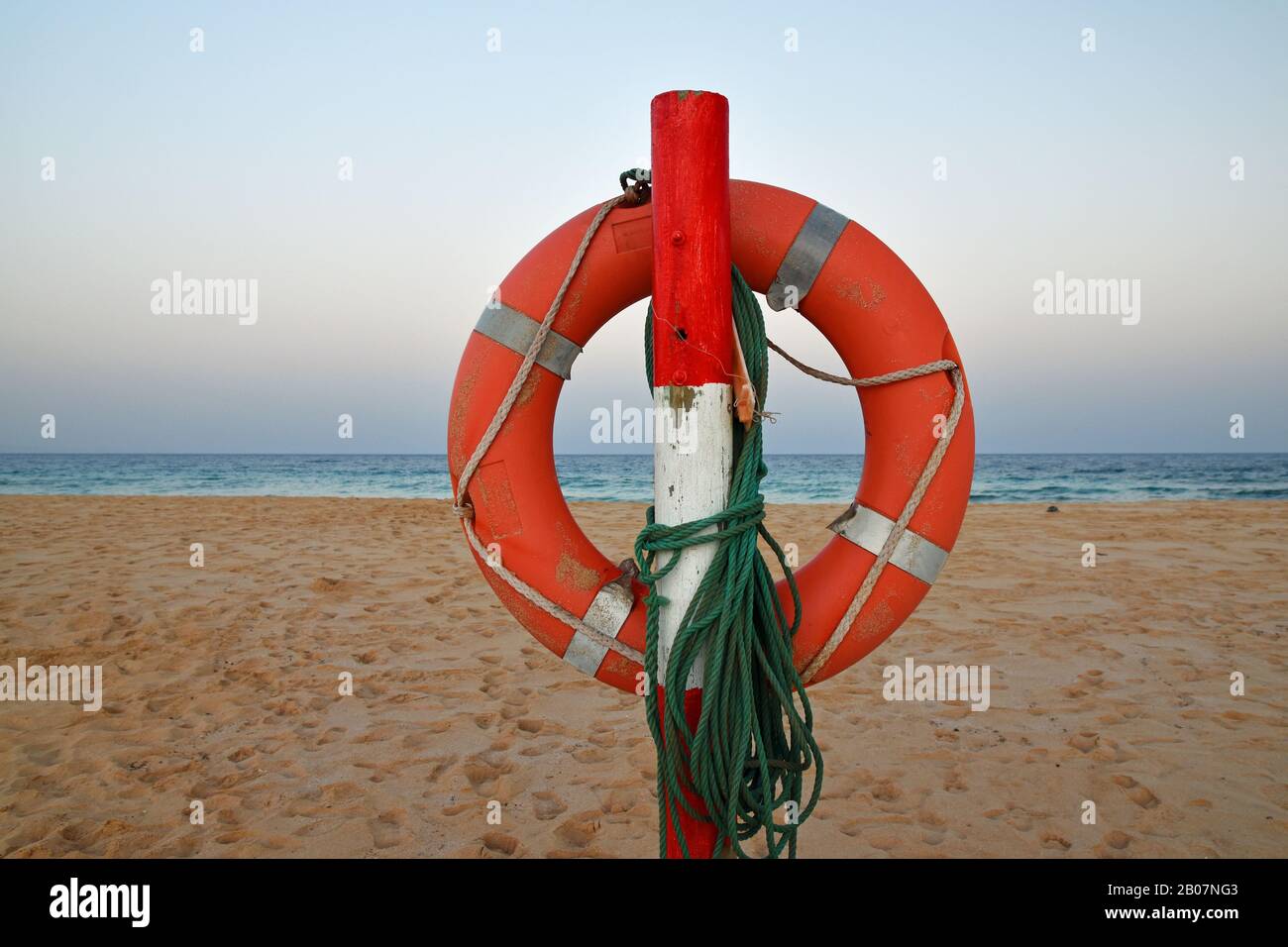 Orange life saver ring on wooden post with green rope on Corralejo ...