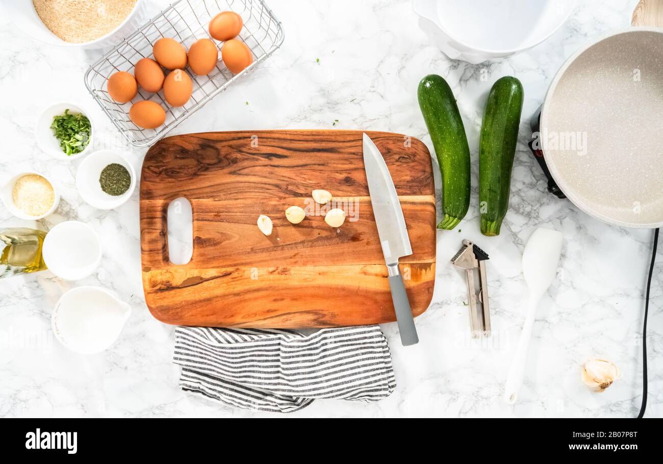 Flat lay. Cutting ingredients on a wood cutting board to make zucchini ...