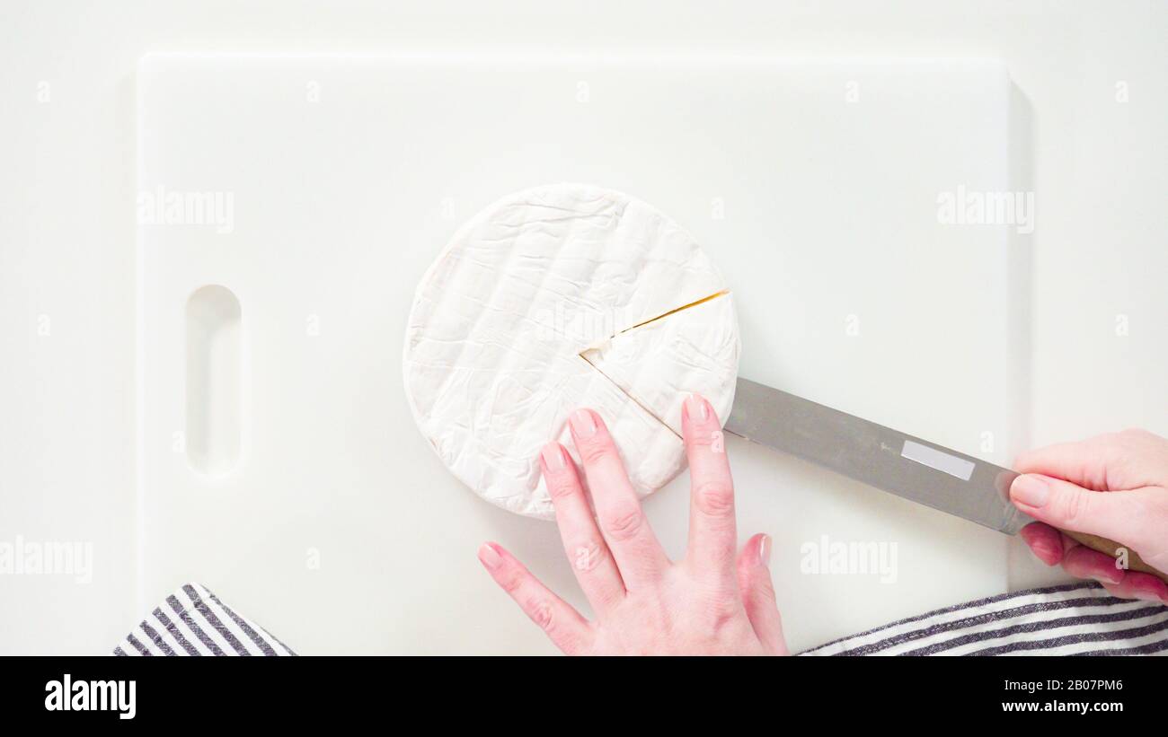 Flat lay. Slicing a large slice of gourmet cheese on a white background ...