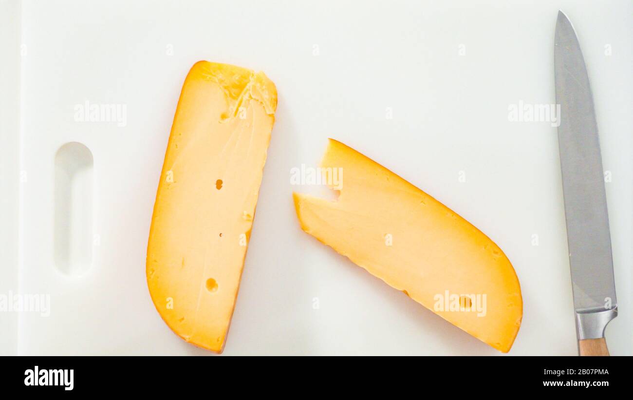 Flat lay. Slicing a large slice of gourmet cheese on a white background ...