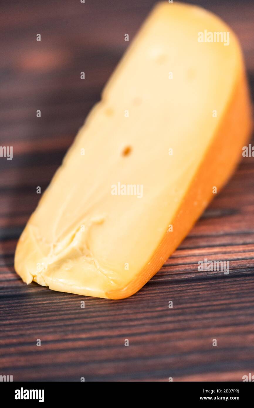 Large wedge of Smoked Gouda cheese on a dark wooden background Stock ...