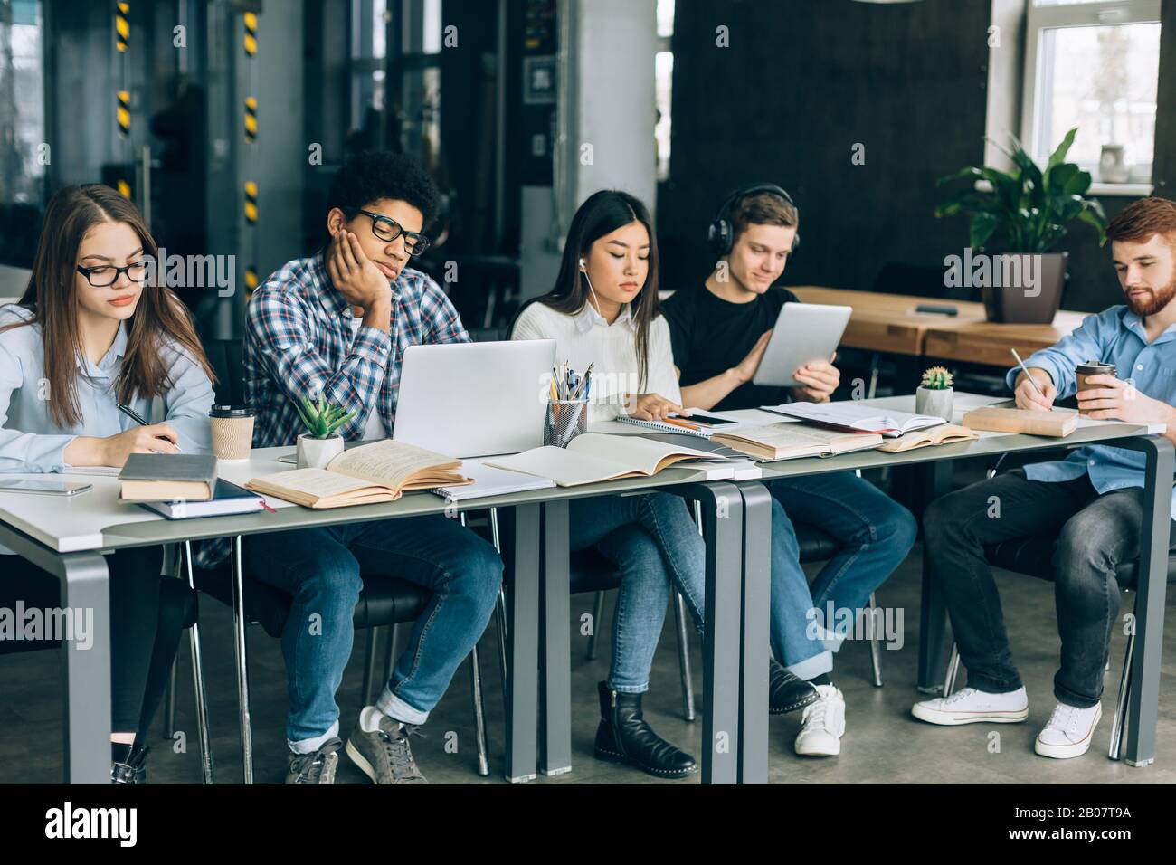 Students in library. Tired teens doing homework Stock Photo - Alamy