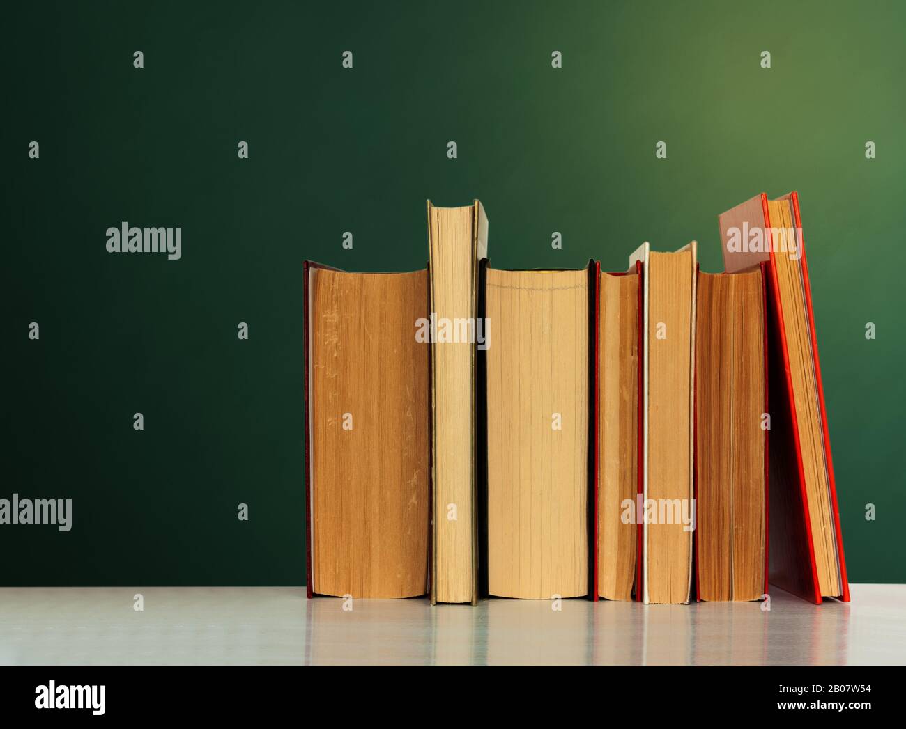 Back to school, pile of books with empty green school board background ...