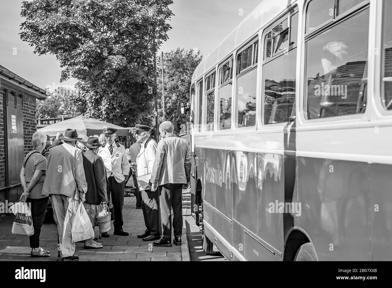 13 group of people in 1940s dress queuing for a classic forties bus ...