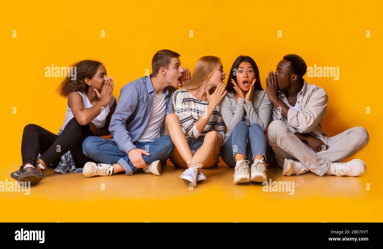 Group of multiracial friends gossiping over yellow background Stock ...