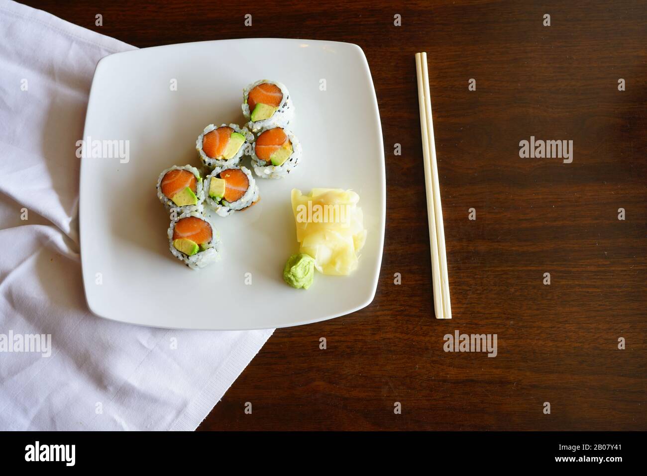 A plate of avocado and salmon sushi roll with pickled ginger and wasabi ...