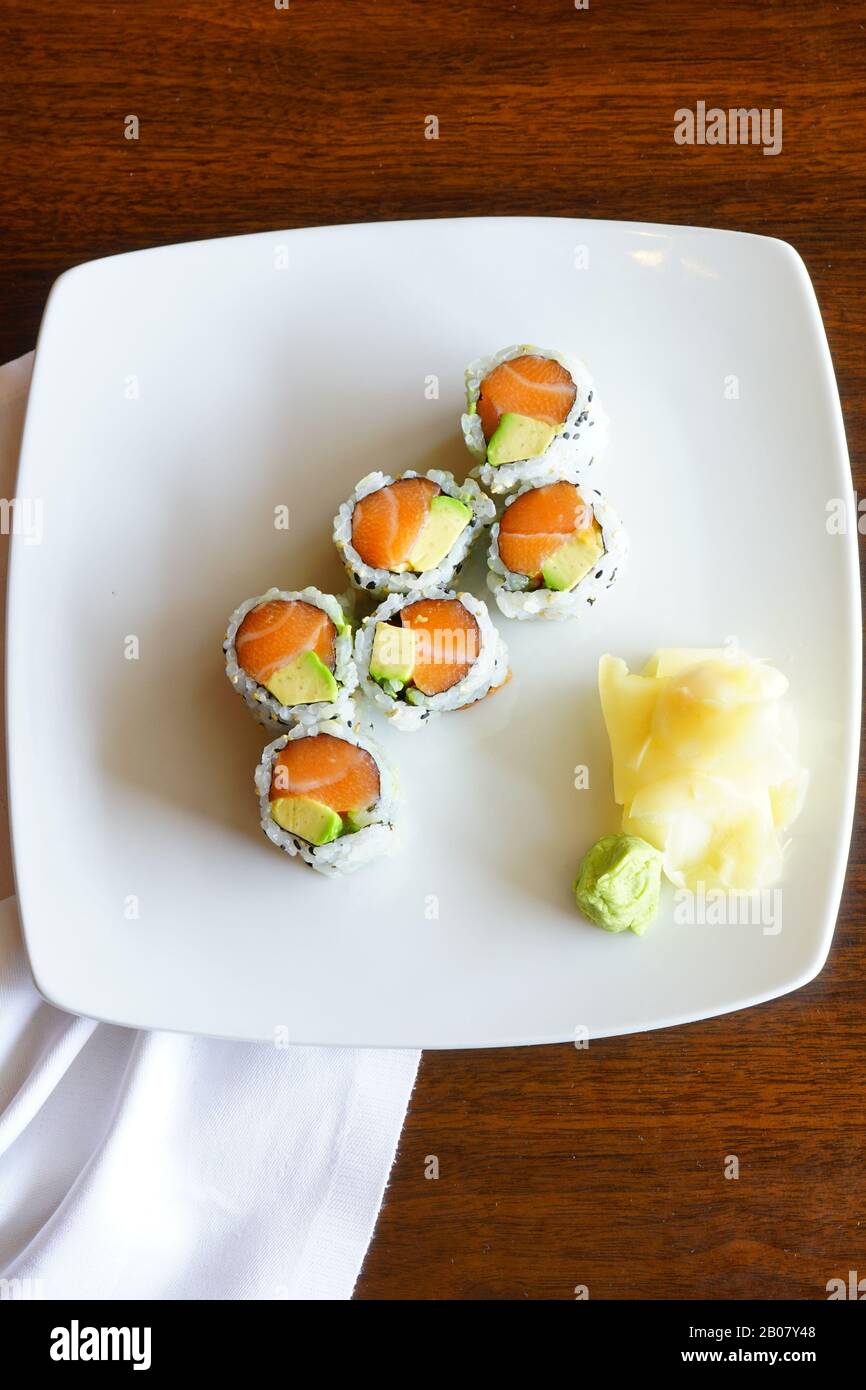 A plate of avocado and salmon sushi roll with pickled ginger and wasabi ...