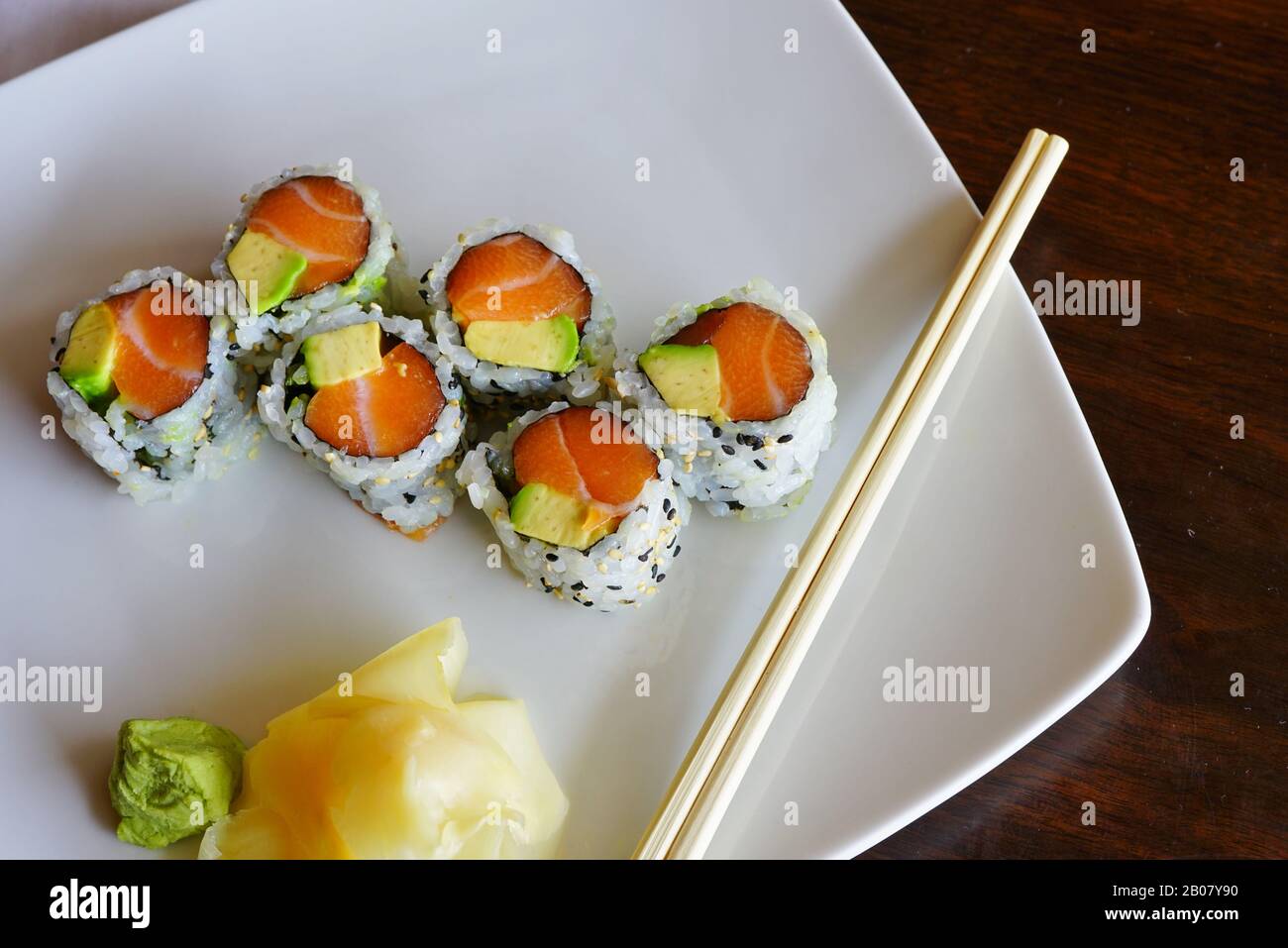 A plate of avocado and salmon sushi roll with pickled ginger and wasabi ...