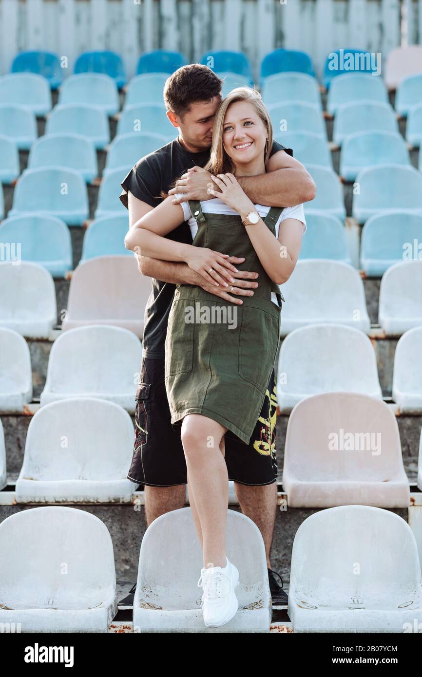 Young couple on a date. Guy with a girl cuddling in the stadium Stock ...