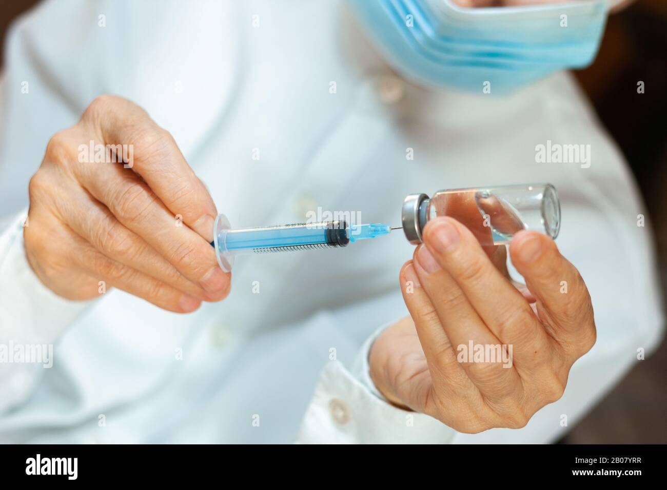 doctor in a white surgical gown and blue mask holds in hands a medical ...