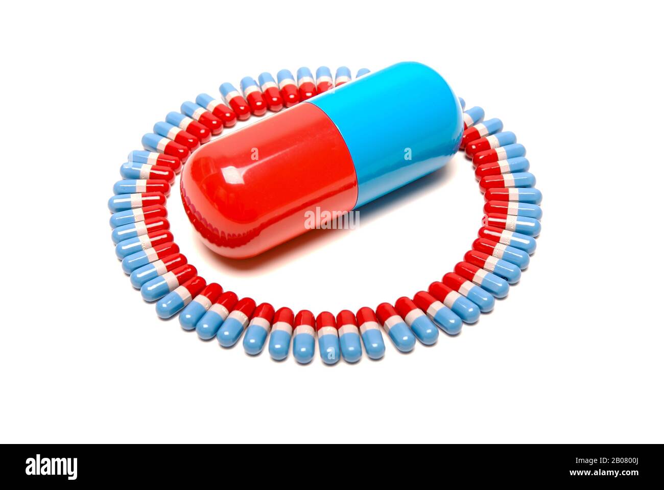 Large colorful capsule encircled by a row of smaller blue and red pills ...