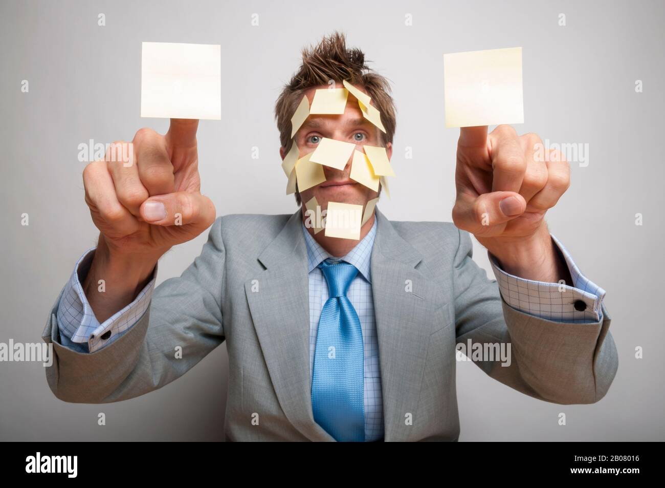 Overworked office worker covered in yellow sticky notes pointing at ...