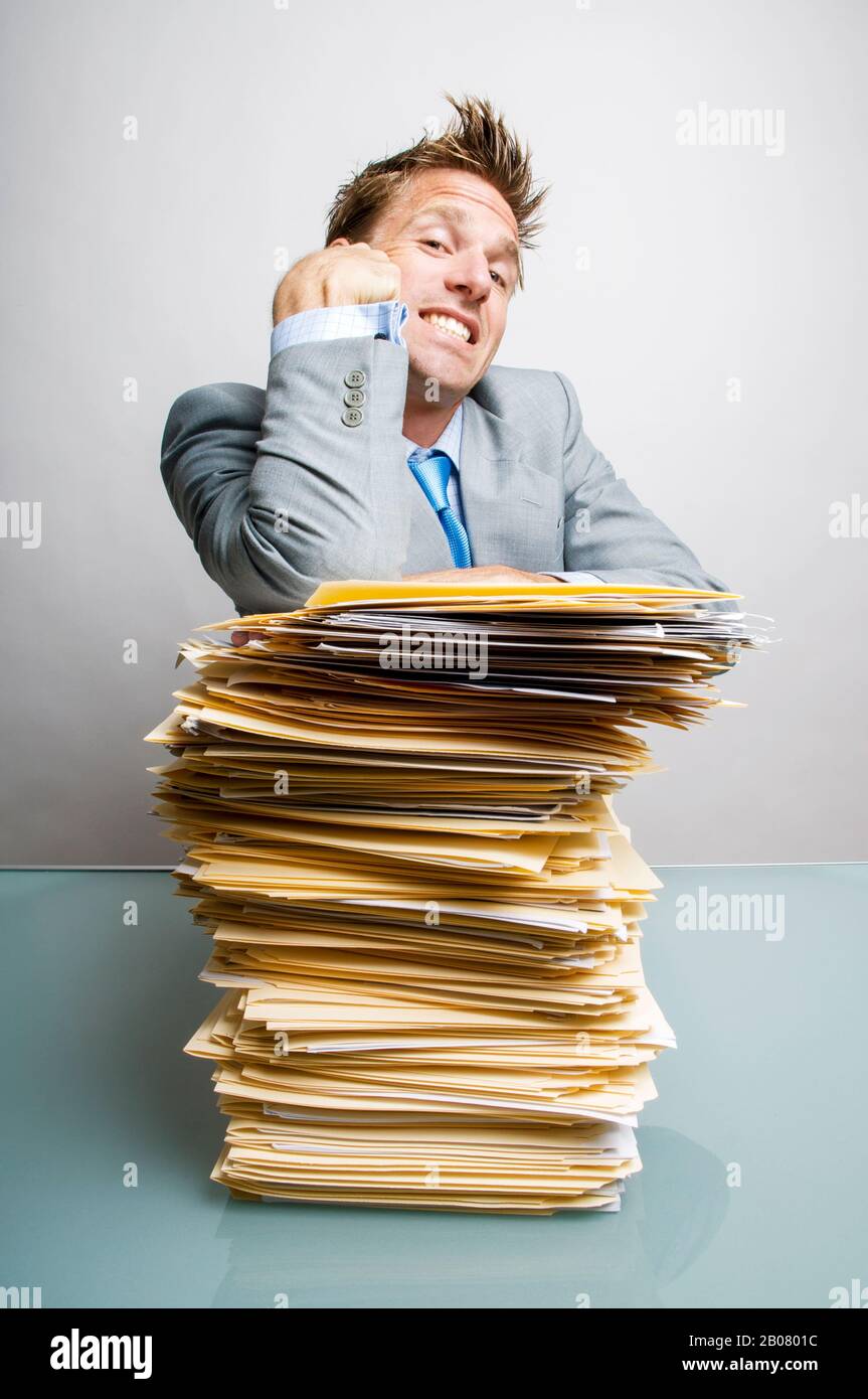 Cheerful office worker resting on a tall stack of completed paperwork ...