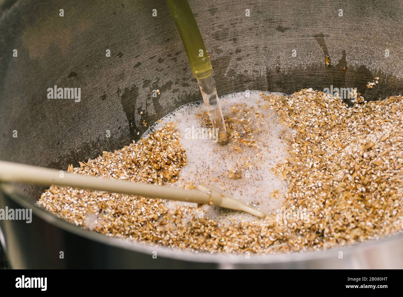 Brewing beer. Stirring the malt with a long stirrer. Water is sprayed ...